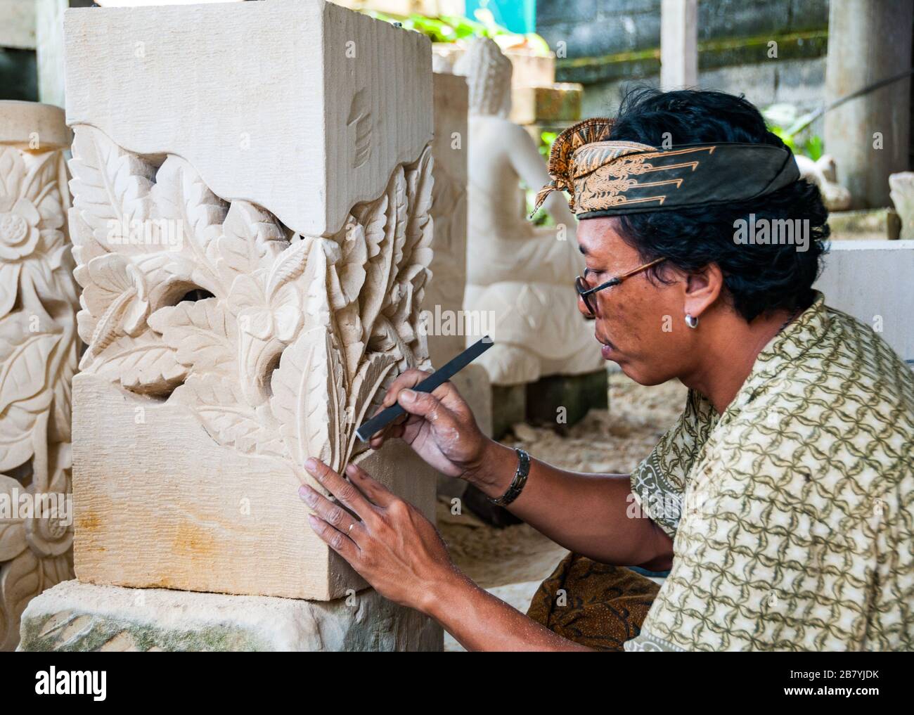 A Balinese artisan hard at work sculpting a statue out of a block of ...