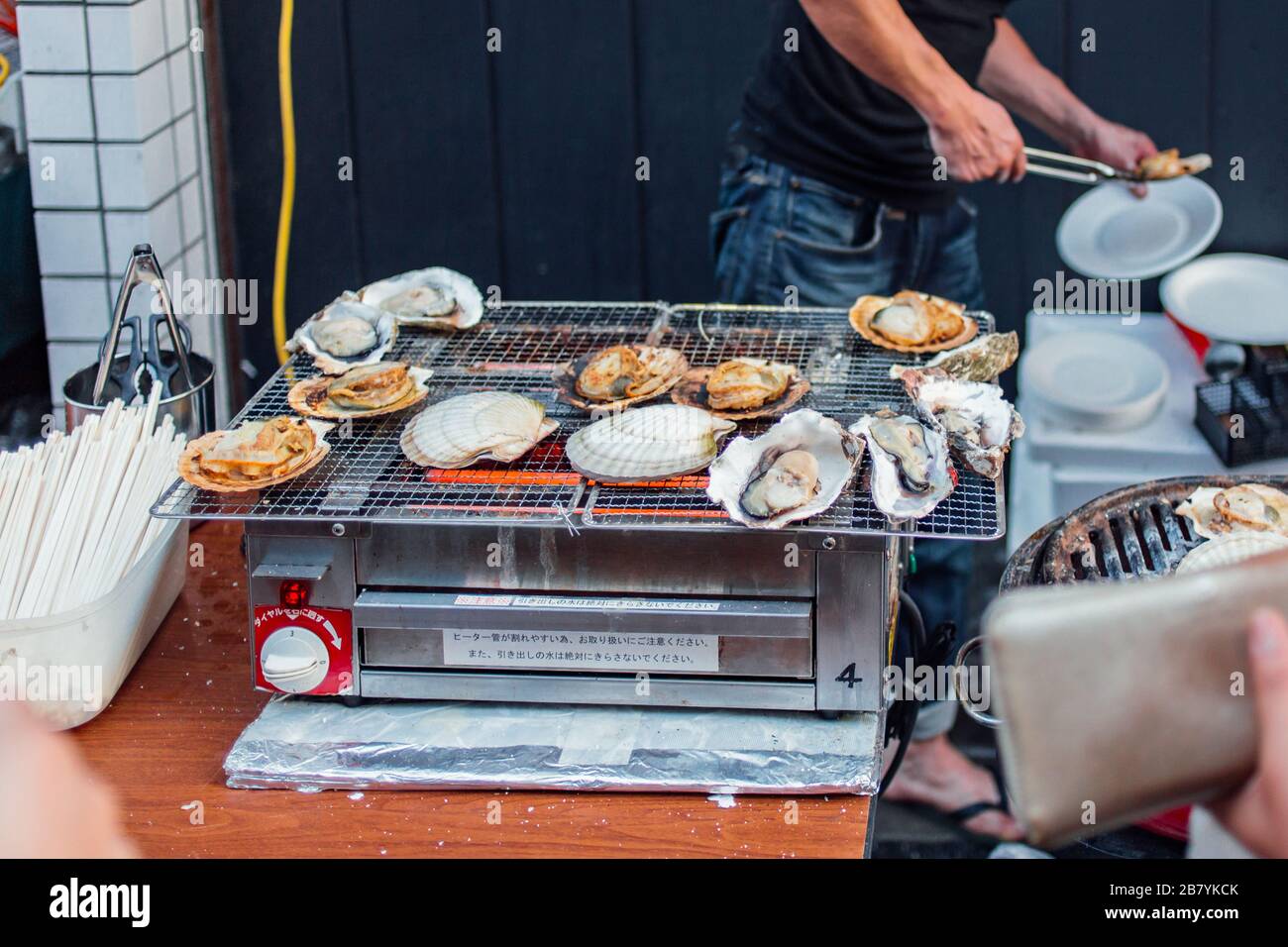 Cooking grilled seashells at Japanese summer festival in a small town ...