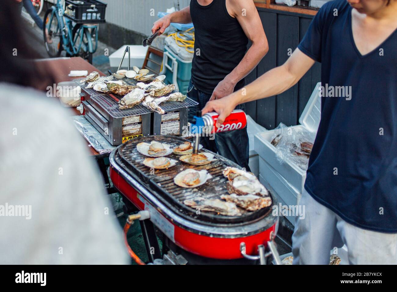 Cooking grilled seashells at Japanese summer festival in a small town ...