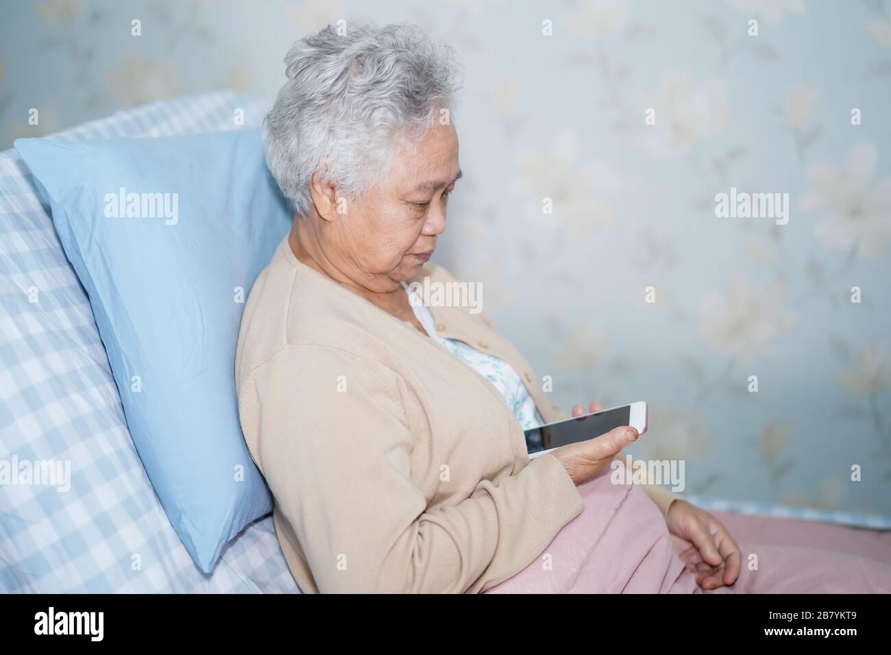 Asian senior or elderly old lady woman patient holding mobile phone ...