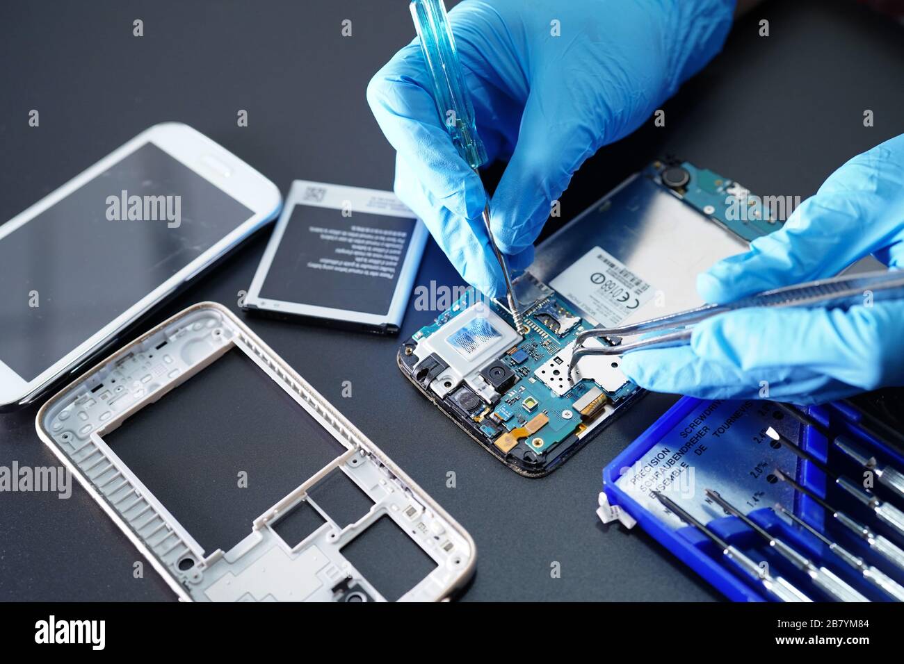 Asian Technician repairing micro circuit main board of smartphone ...