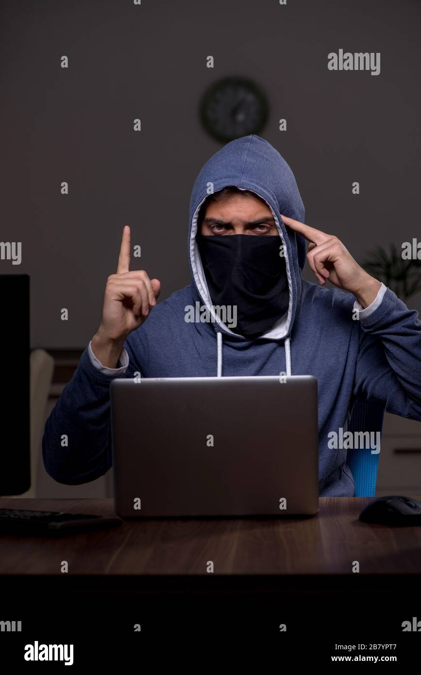 Male hacker hacking security firewall late in the office Stock Photo ...