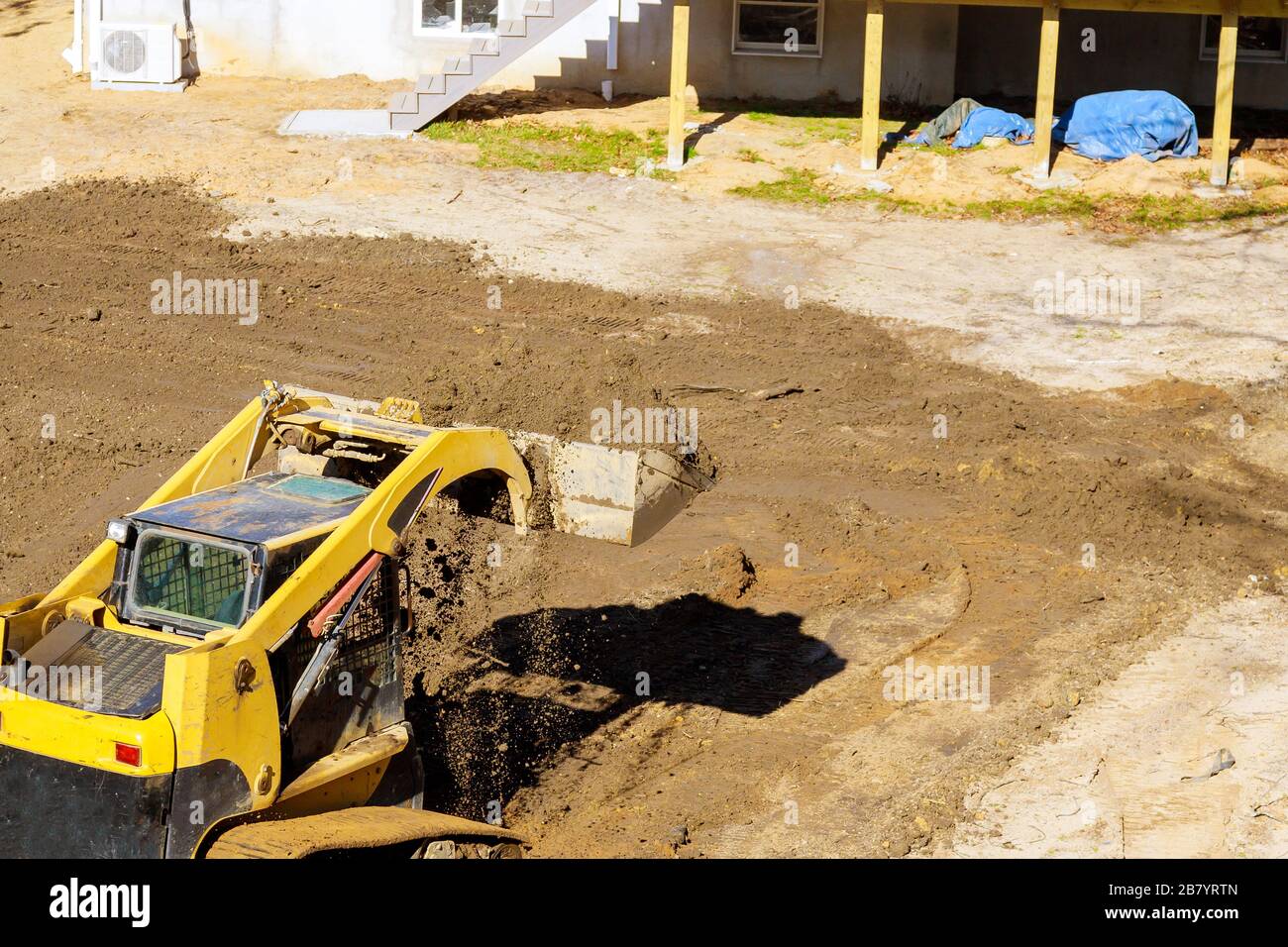 Mini bulldozer with earth doing landscaping works level the ground ...