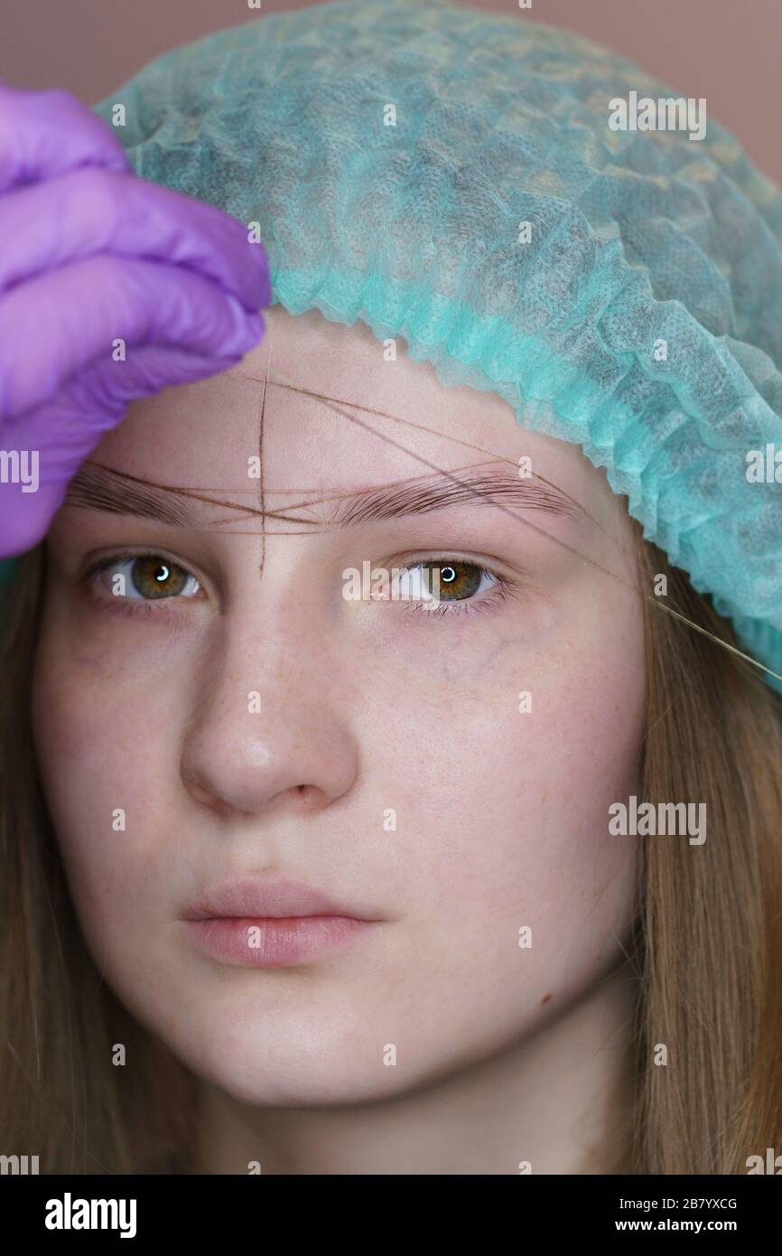 Microbleeding and eyebrow architecture. Beautician builds lines of ...