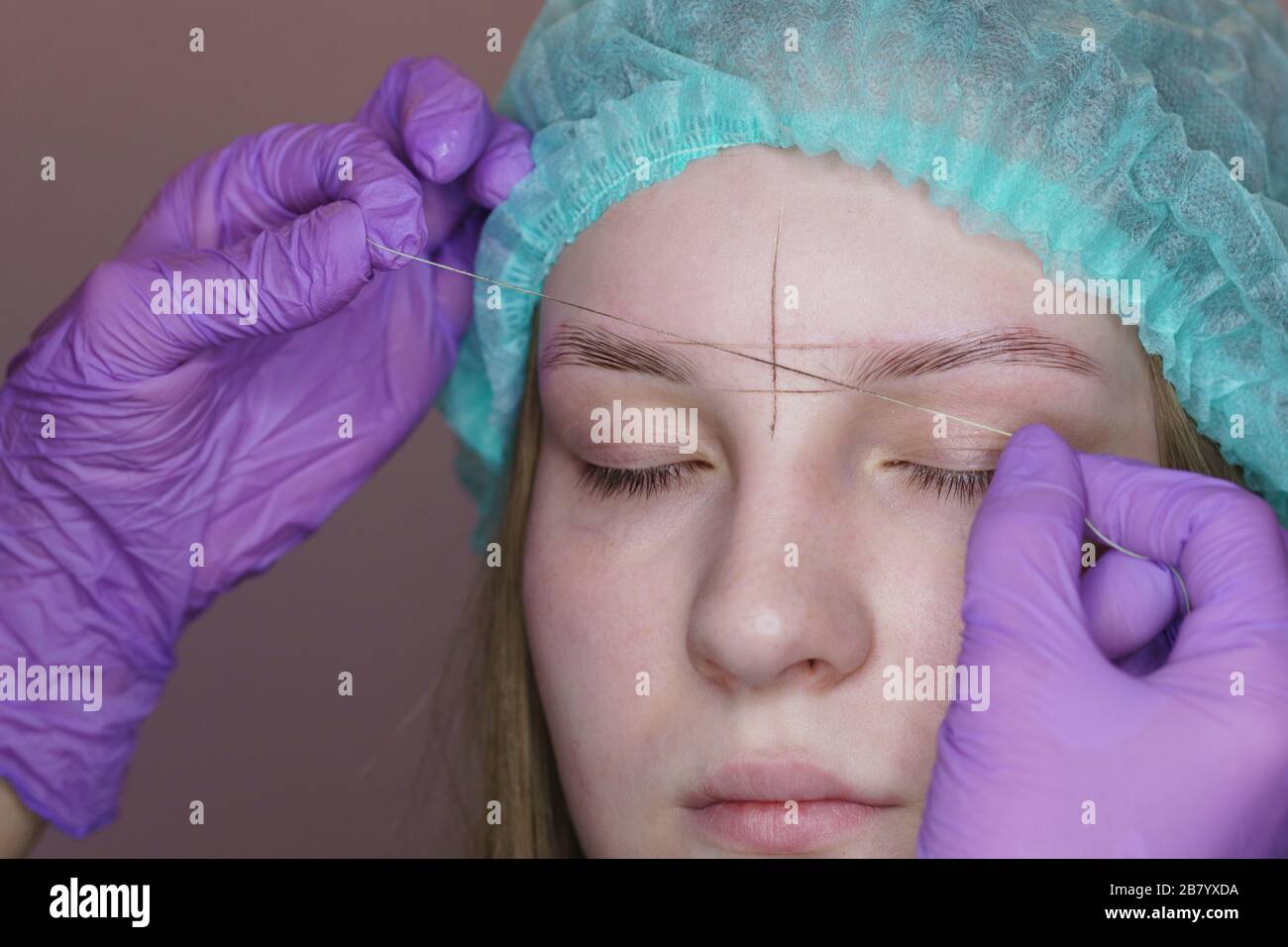 Microbleeding and eyebrow architecture. Beautician builds lines of ...