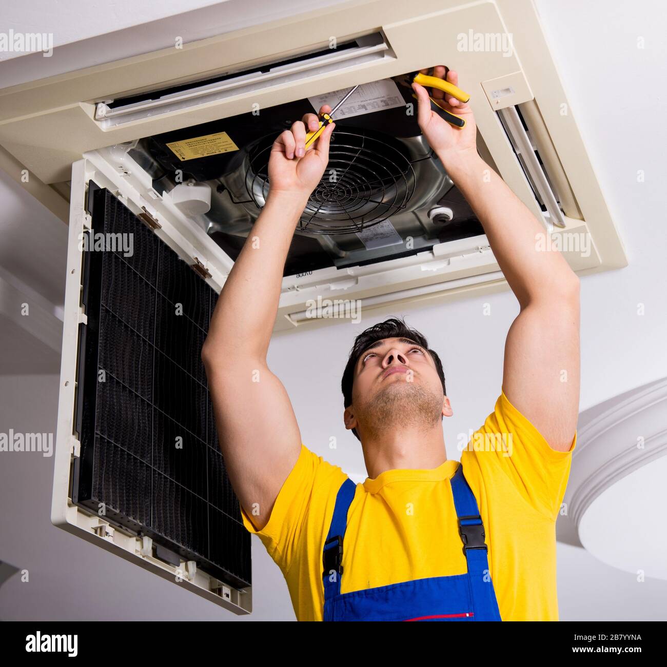 The repairman repairing ceiling air conditioning unit Stock Photo - Alamy