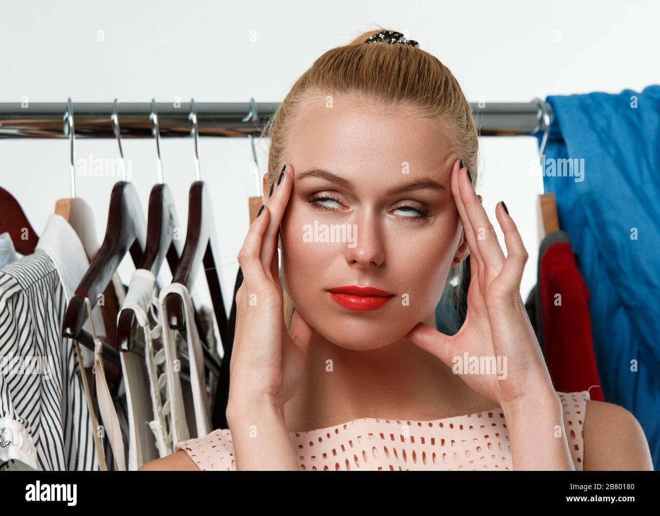 Beautiful blonde woman suffering near wardrobe rack Stock Photo - Alamy