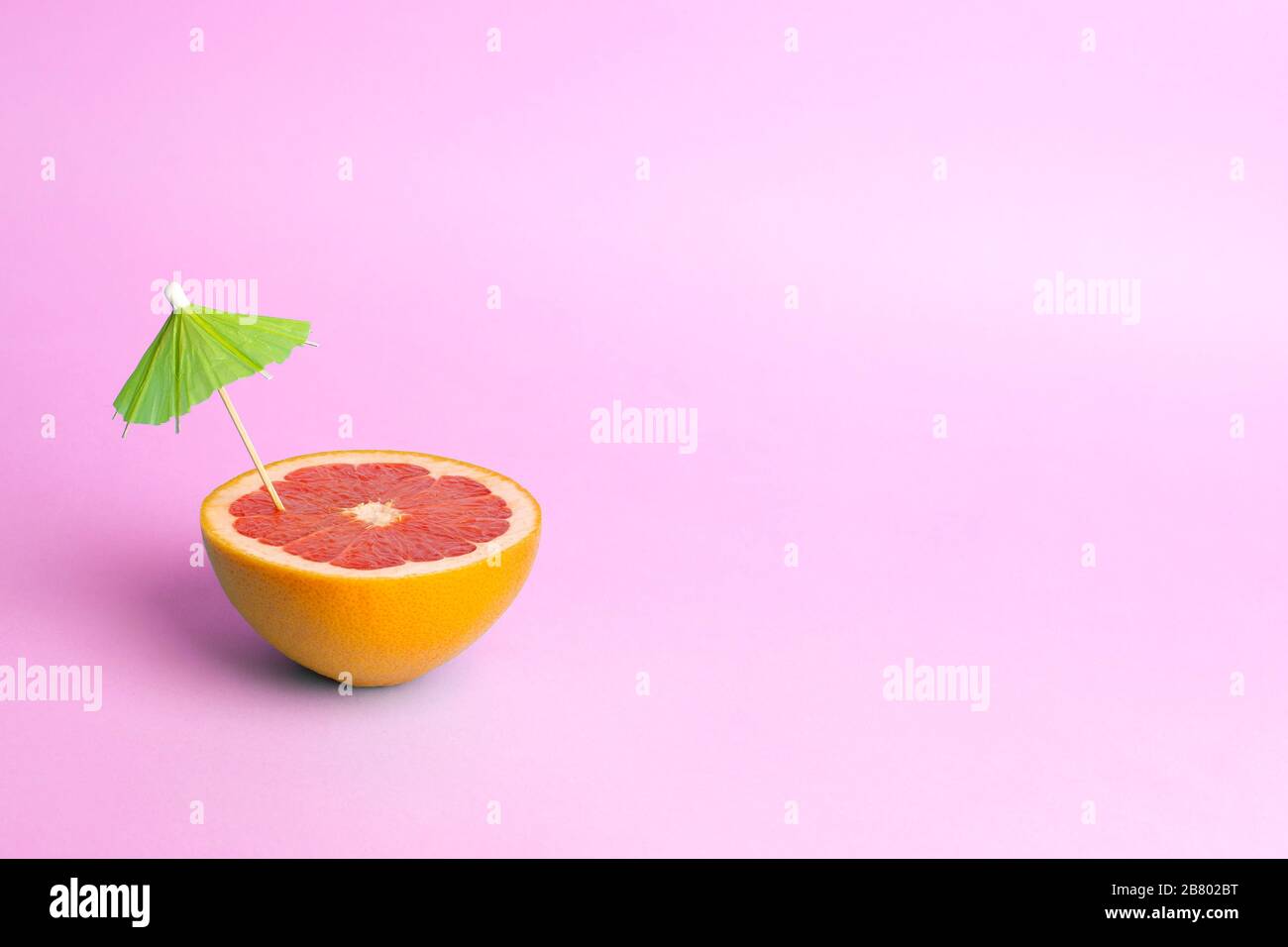 Summer vacation concept. Grapefruit with a cocktail umbrella on a ...