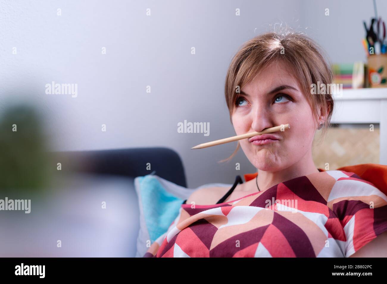 Young Caucasian man is fooling around and home, pencil trapped between ...