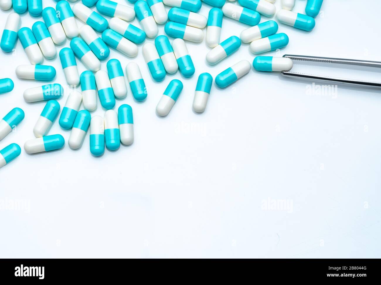 Forceps pick white-blue capsule from group of capsule pills. Drugs ...