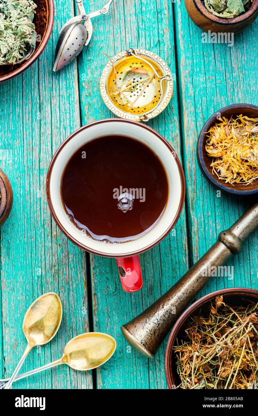 Cup with useful tea from medicinal herbs on a wooden background.Various ...