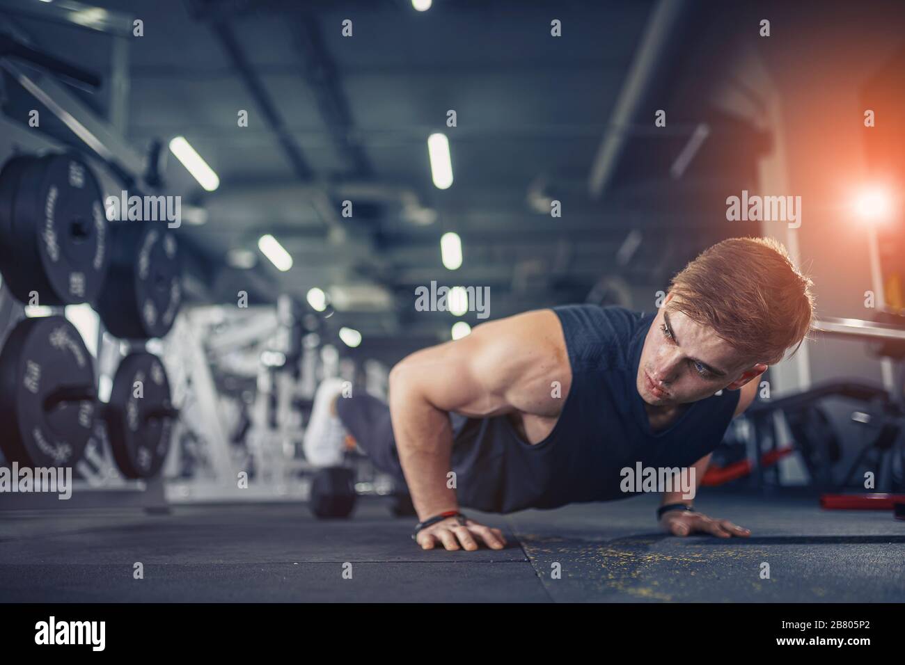 Young athletic man doing push-ups in gym. Muscular and strong guy ...