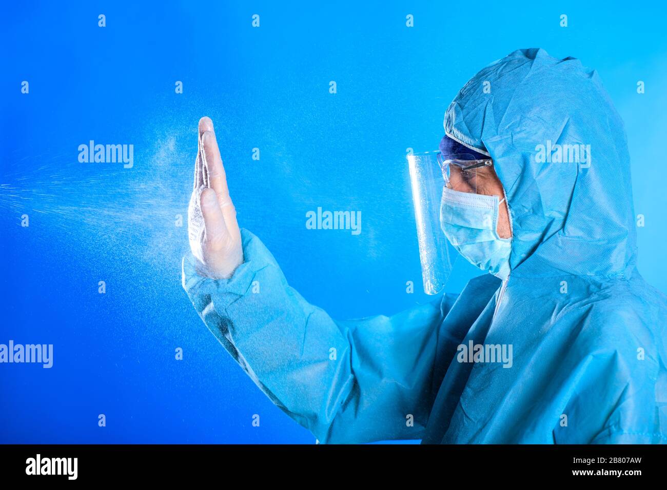 man in a blue full protected suit with disinfectant , conavirus ...