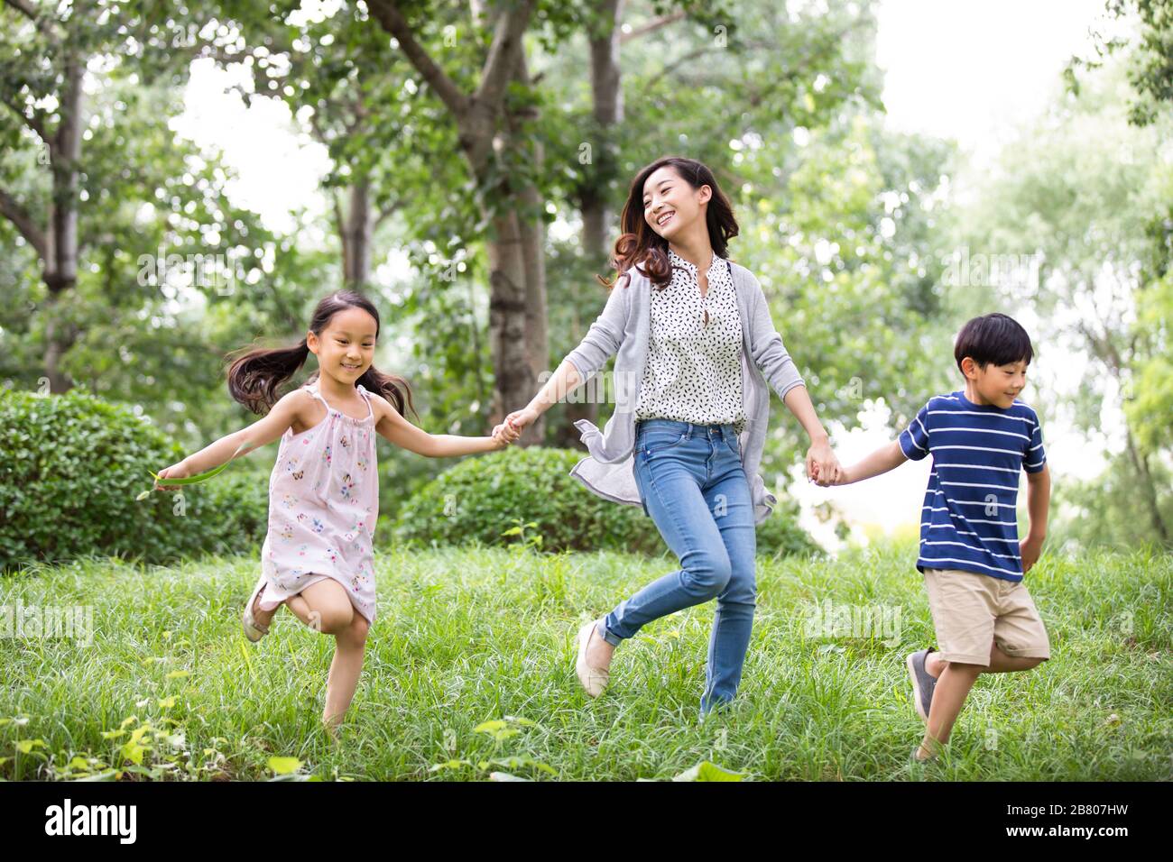 Happy young Chinese family running on grass Stock Photo - Alamy