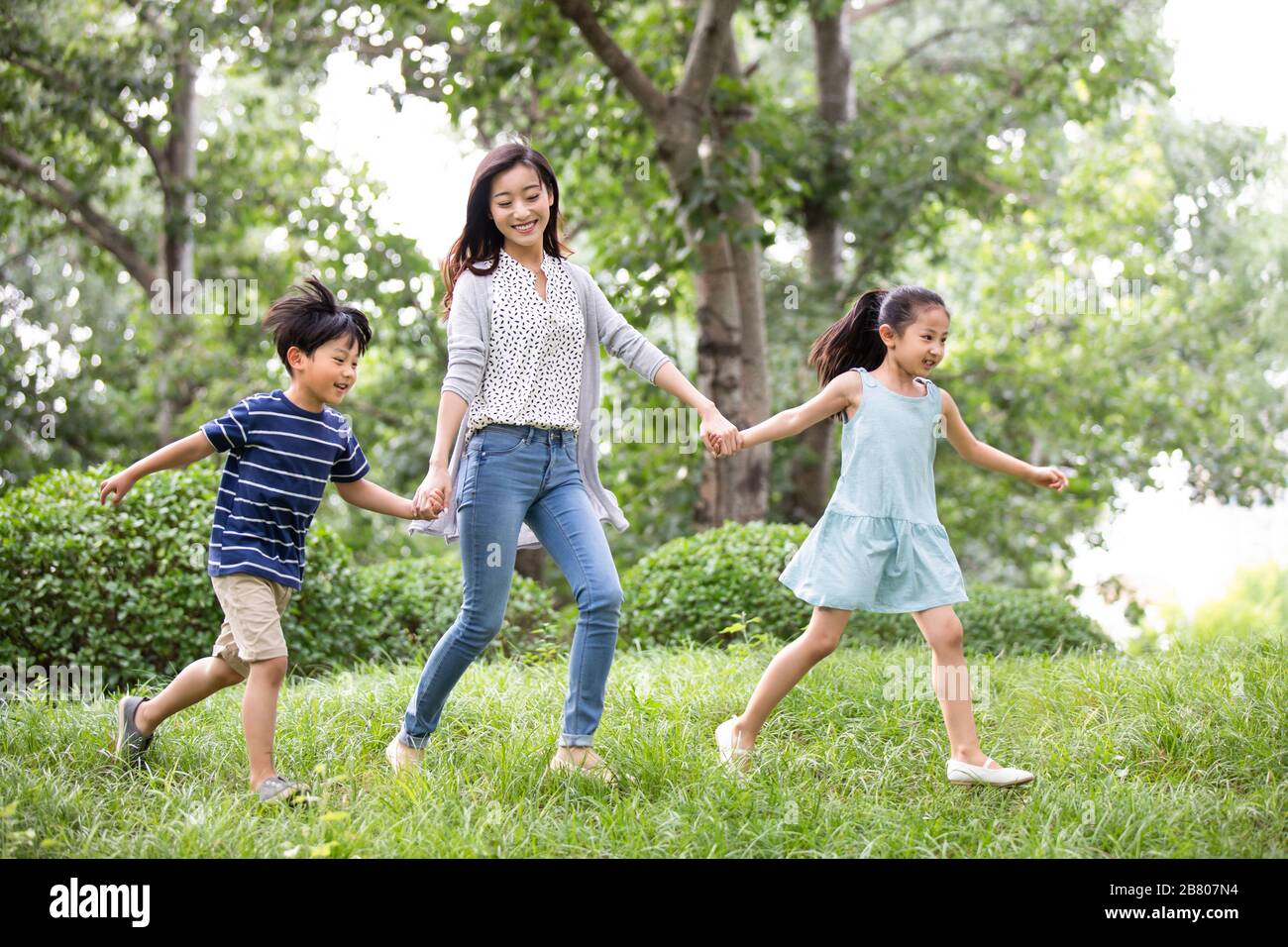Happy young Chinese family running on grass Stock Photo - Alamy
