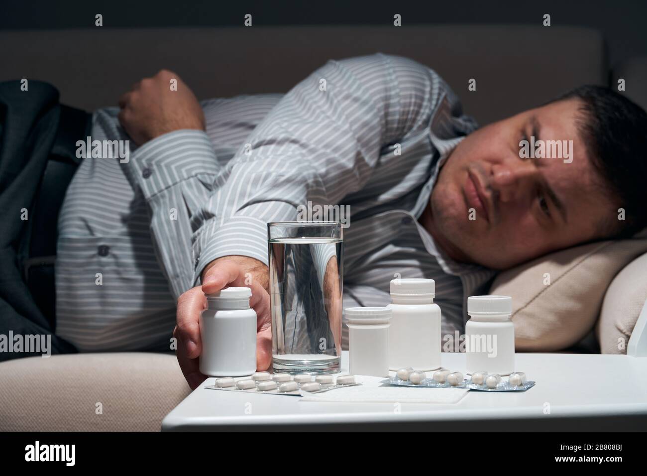 Overworked businessman is lying on the sofa and resting. Pills and ...
