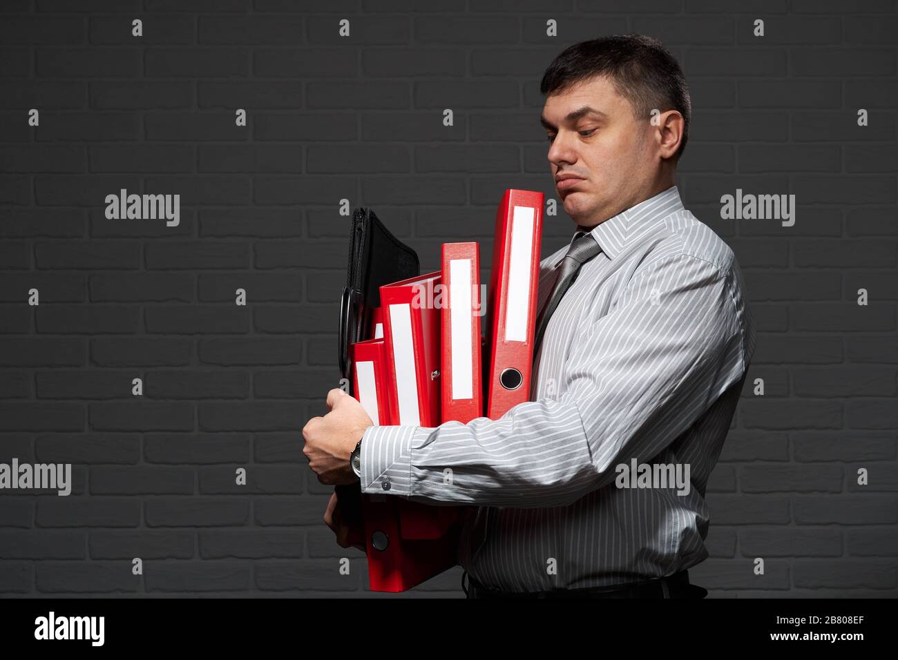 Very busy businessman closeup portrait, posing with red folders ...