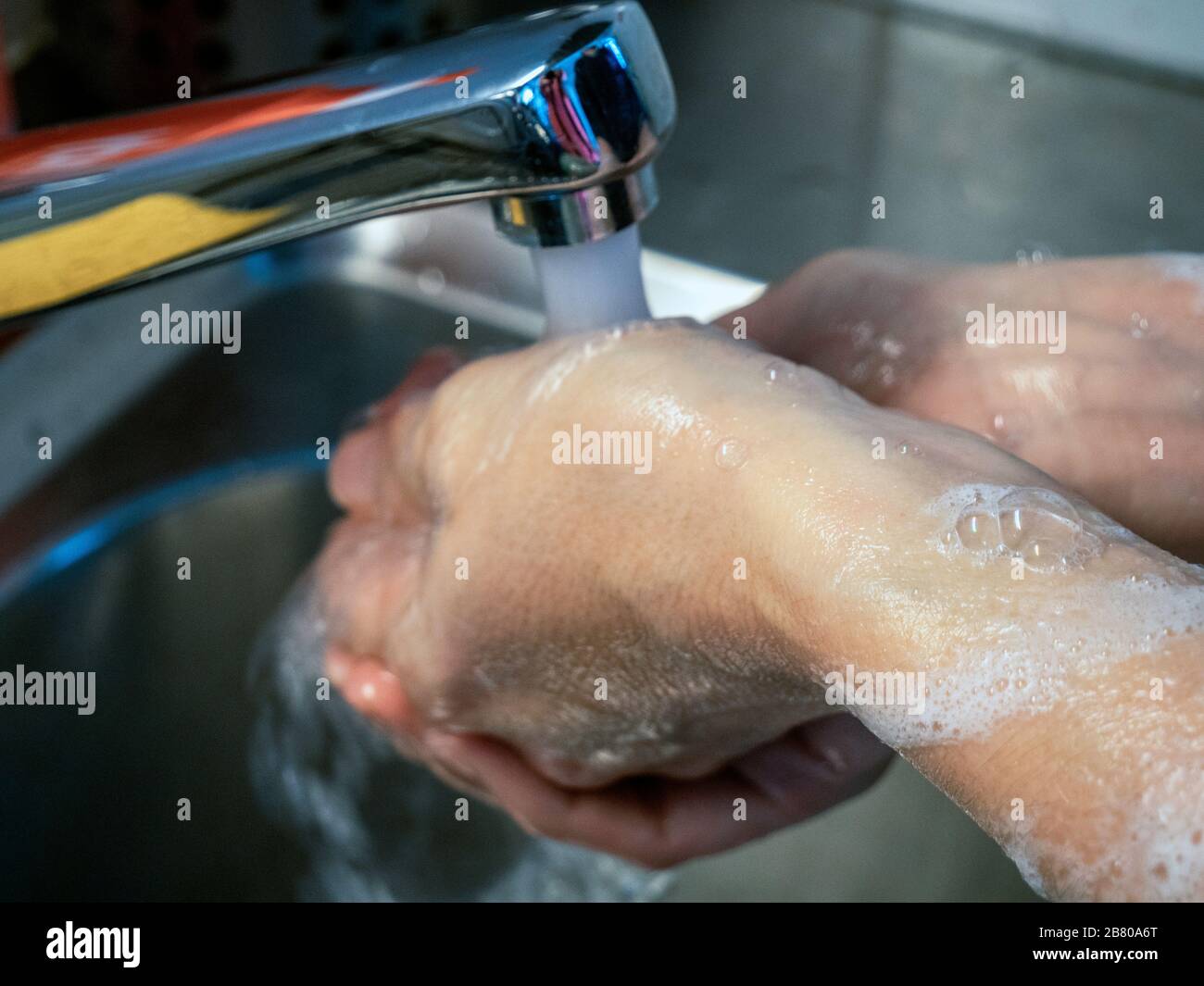 A female thoroughly washes her hands at a kitchen sink. She firsts uses ...