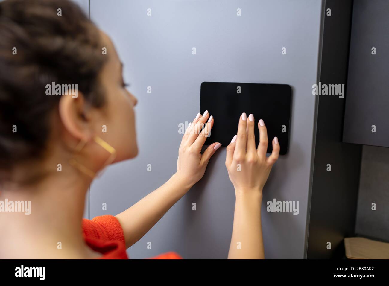 Woman hands holding tablet against grey wall Stock Photo - Alamy