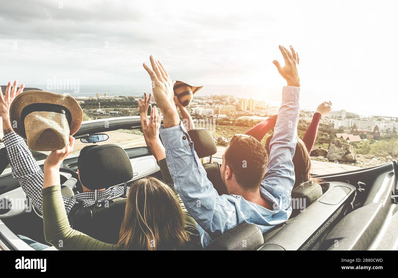 Happy friends with hands up having fun in convertible car on summer ...