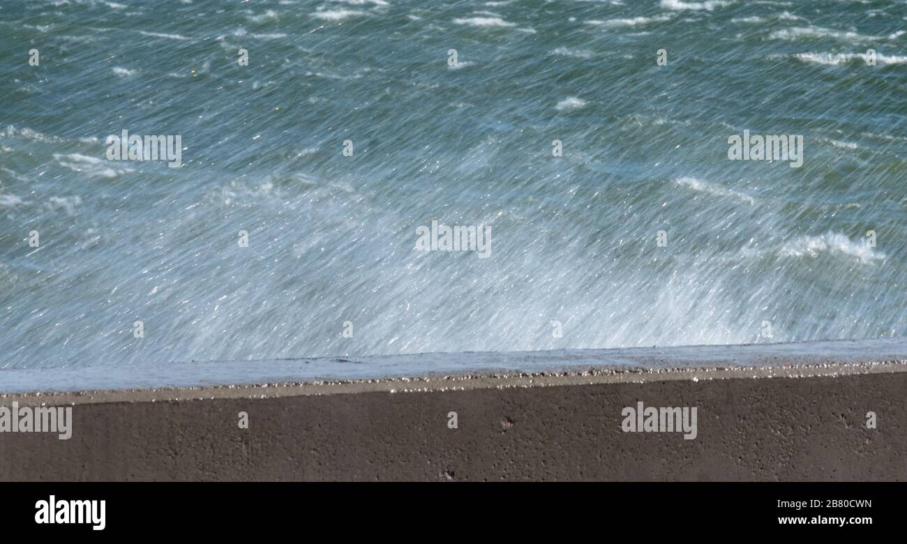Waves hit the hard surface of concrete wall and splashing sea water ...