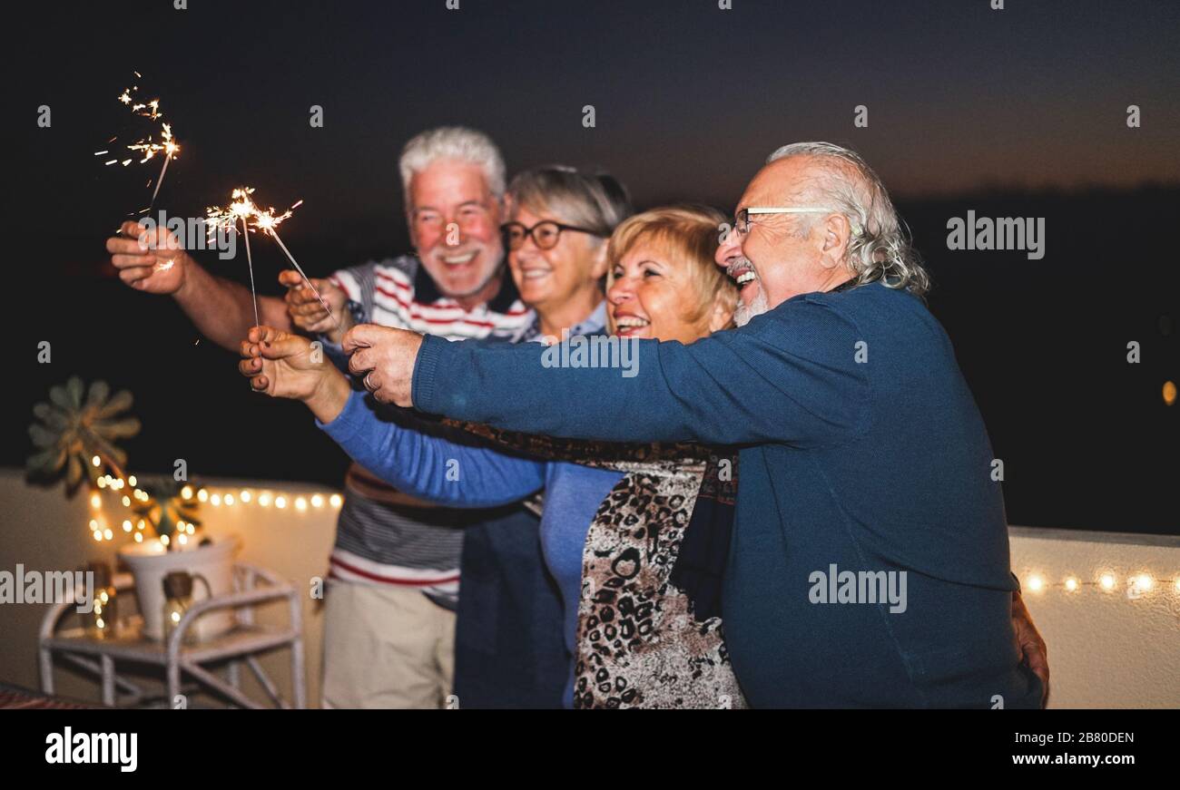 Pensioner friends having fun with fireworks sparklers - Senior people ...