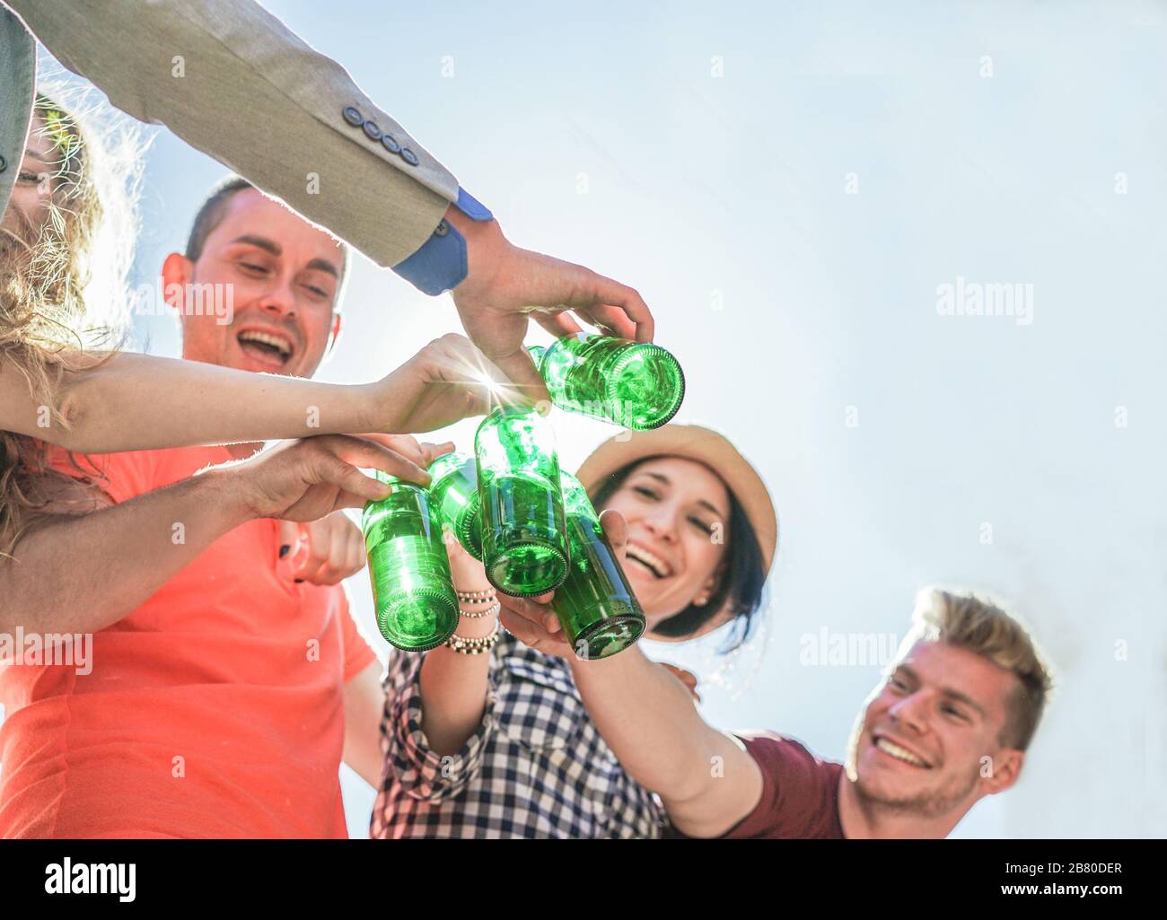Happy friends cheering with beer bottles at party outdoor - Young ...