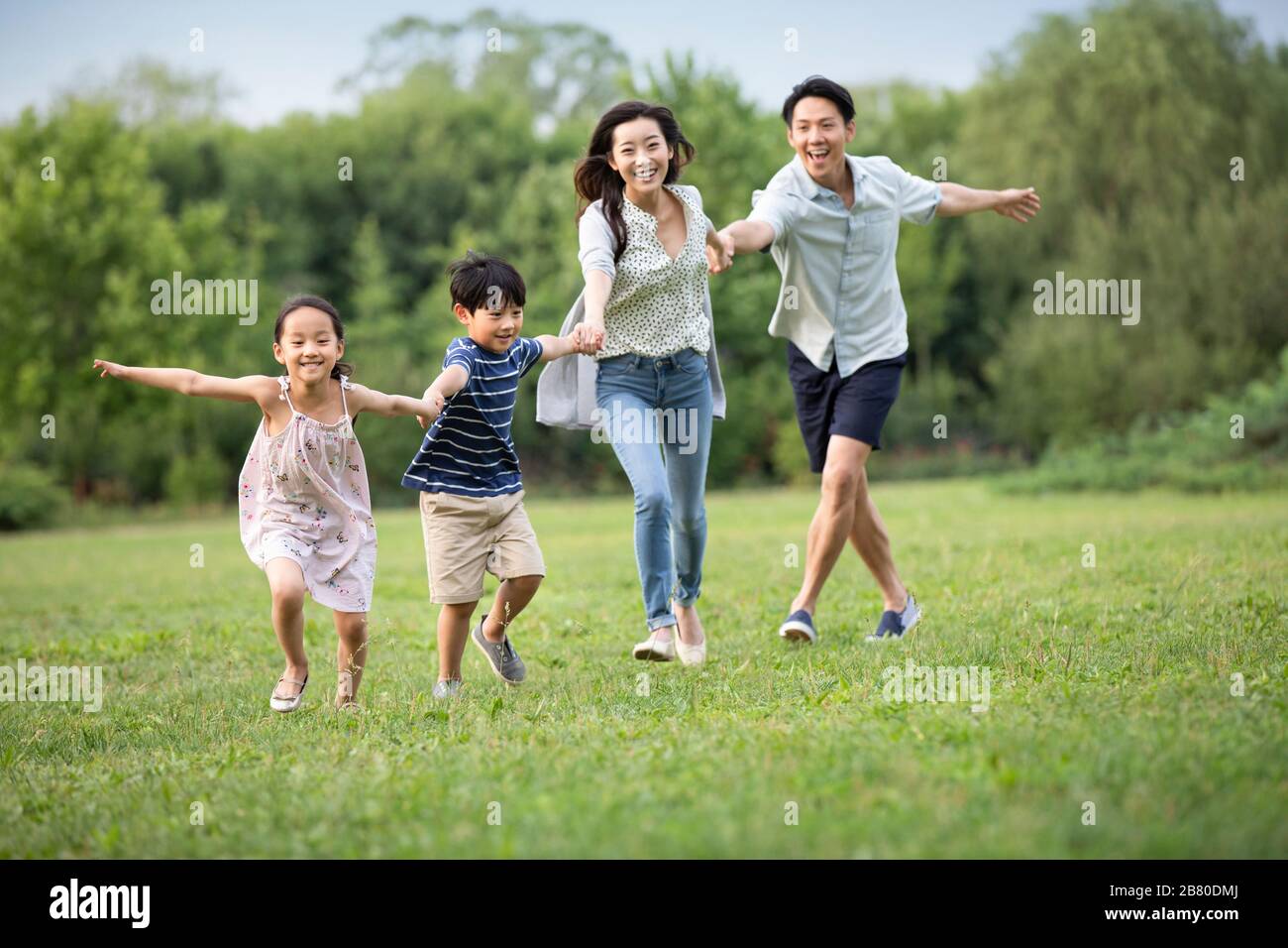 Happy young Chinese family running on grass Stock Photo - Alamy
