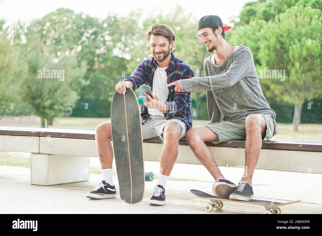 Happy skaters having fun watching videos in smartphone at city park ...
