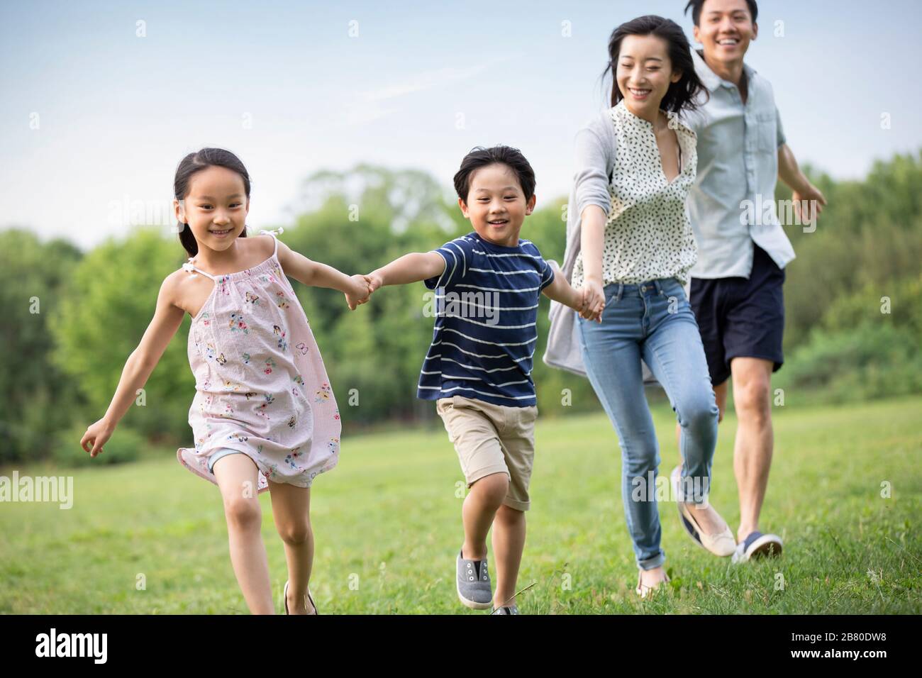 Happy young Chinese family running on grass Stock Photo - Alamy