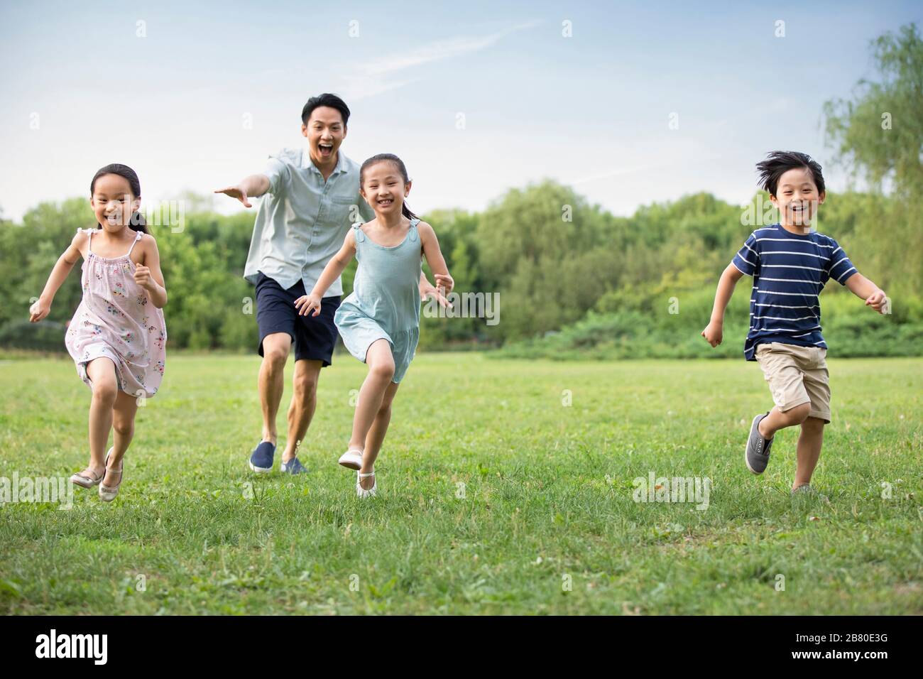 Happy young Chinese family running on grass Stock Photo - Alamy