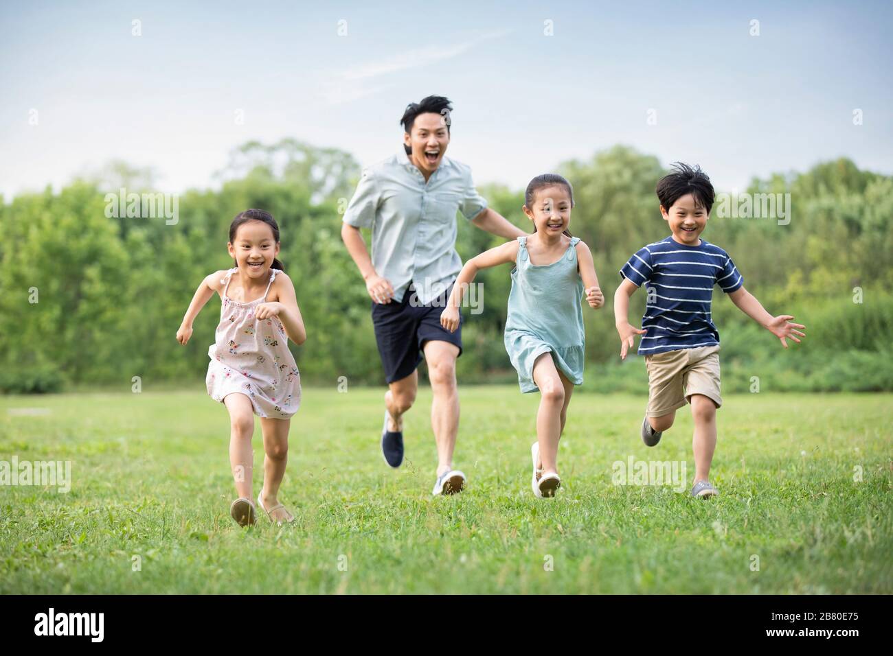 Happy young Chinese family running on grass Stock Photo - Alamy