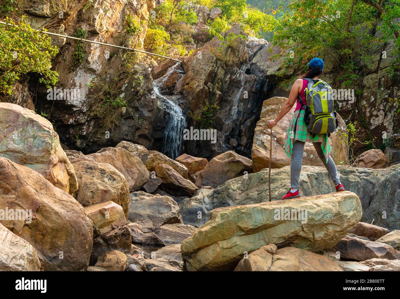An Indian Solo Lady Traveler enjoying the view of a Waterfall carrying ...