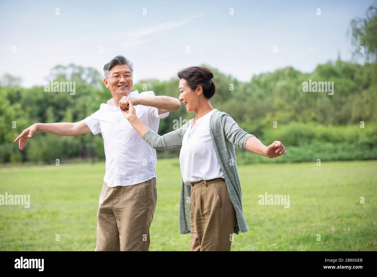Happy senior Chinese couple dancing on grass Stock Photo - Alamy