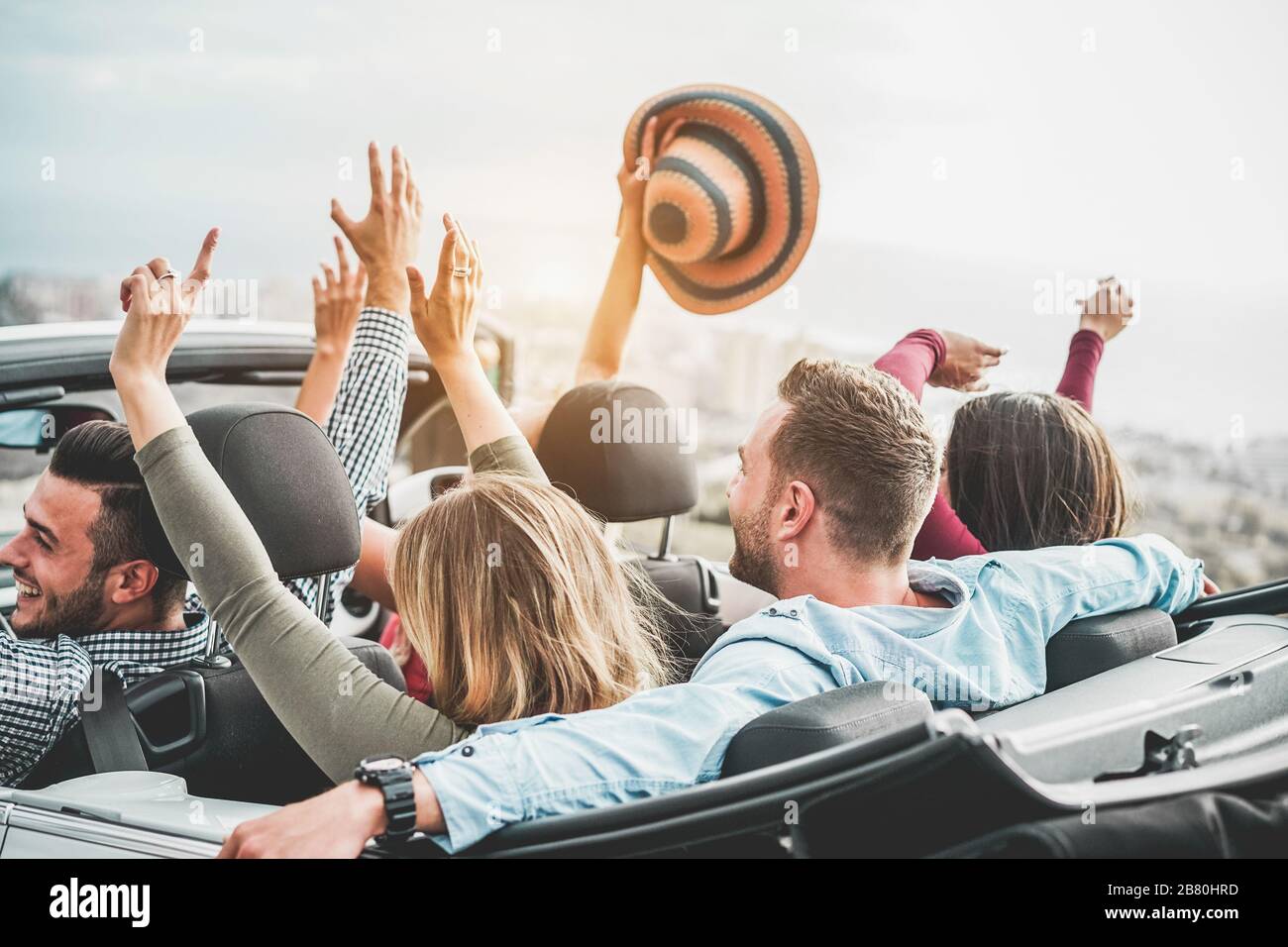 Happy friends with hands up having fun in convertible car on summer ...