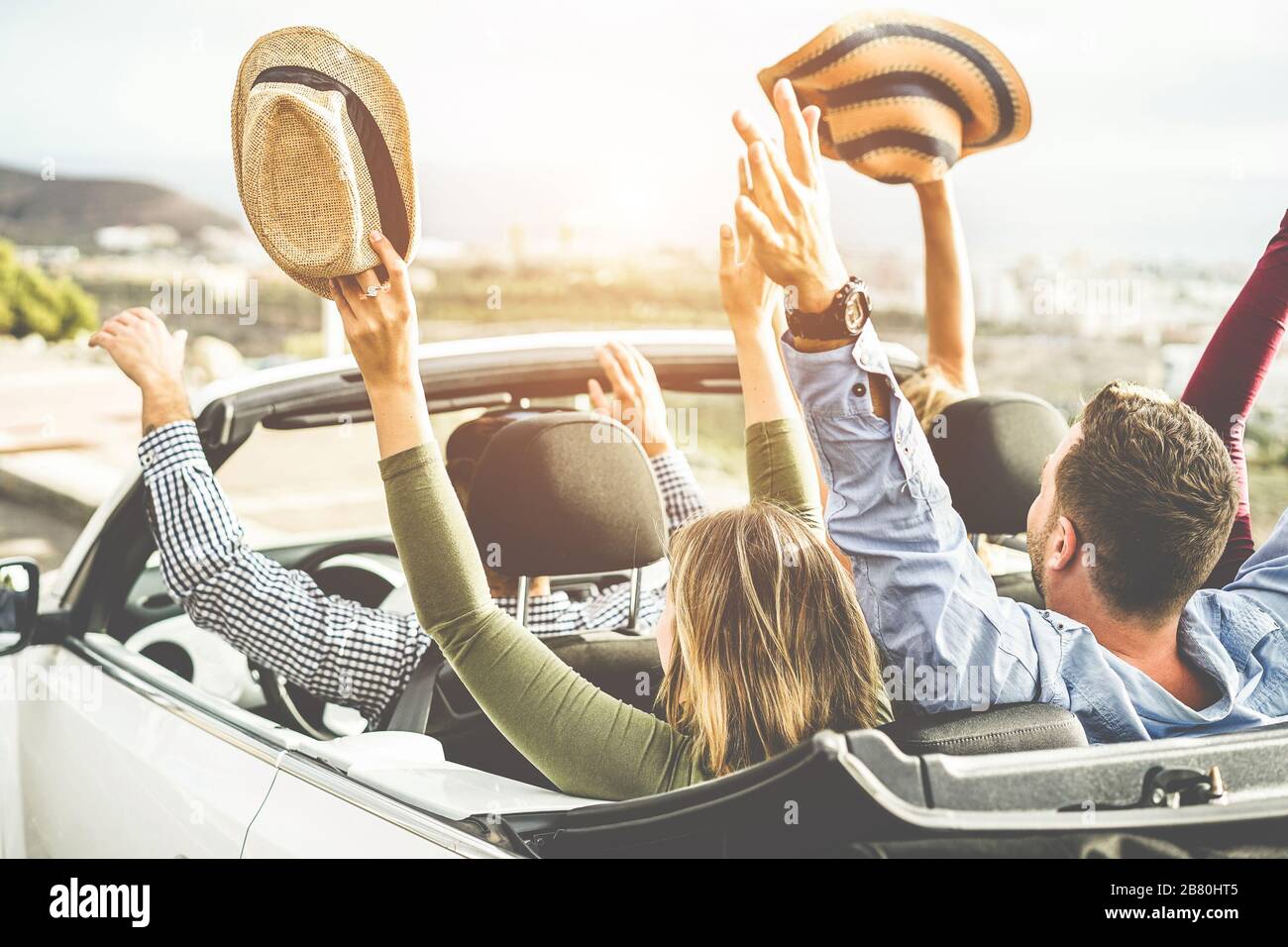 Happy friends with hands up having fun in convertible car on summer ...