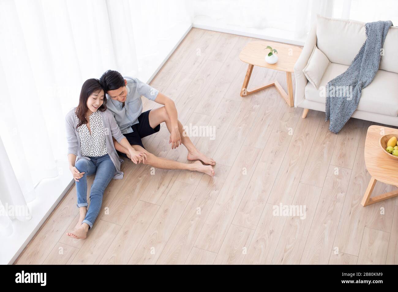 Happy young Chinese couple sitting on floor Stock Photo - Alamy