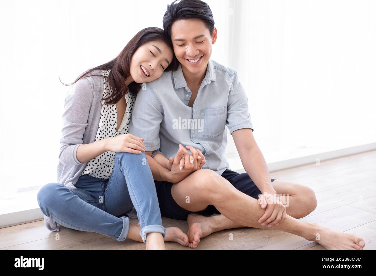 Happy young Chinese couple sitting on floor Stock Photo - Alamy