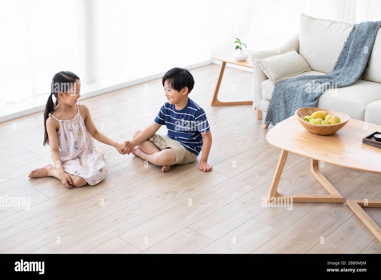 Happy Chinese sibling holding hands in living room Stock Photo - Alamy