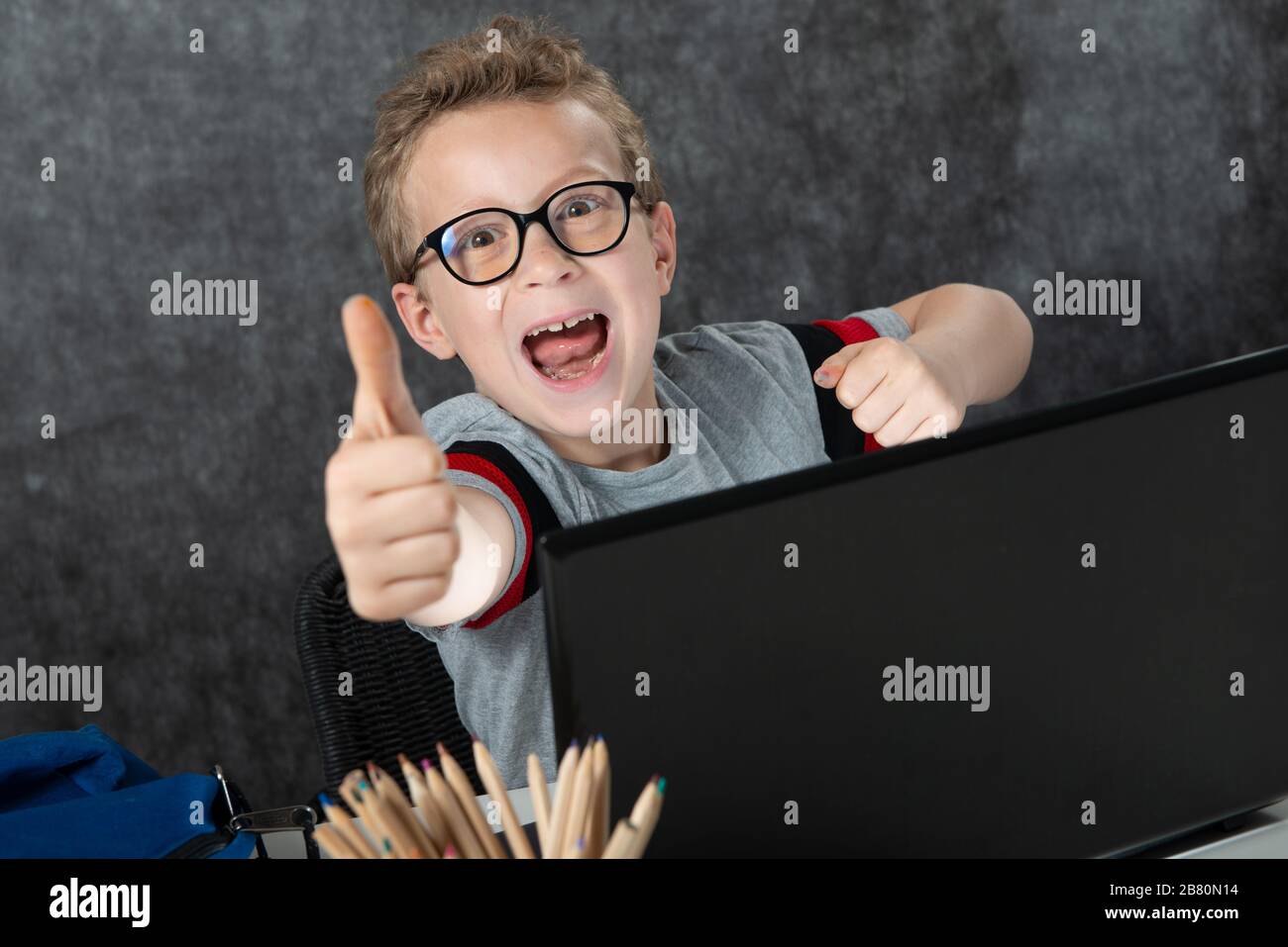a little school boy with laptop showing OK gesture Stock Photo - Alamy