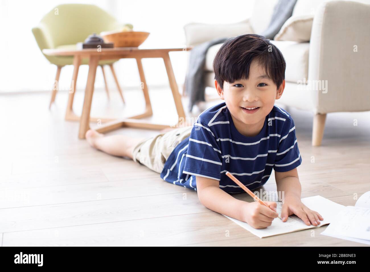 Little Chinese boy doing homework in living room Stock Photo - Alamy
