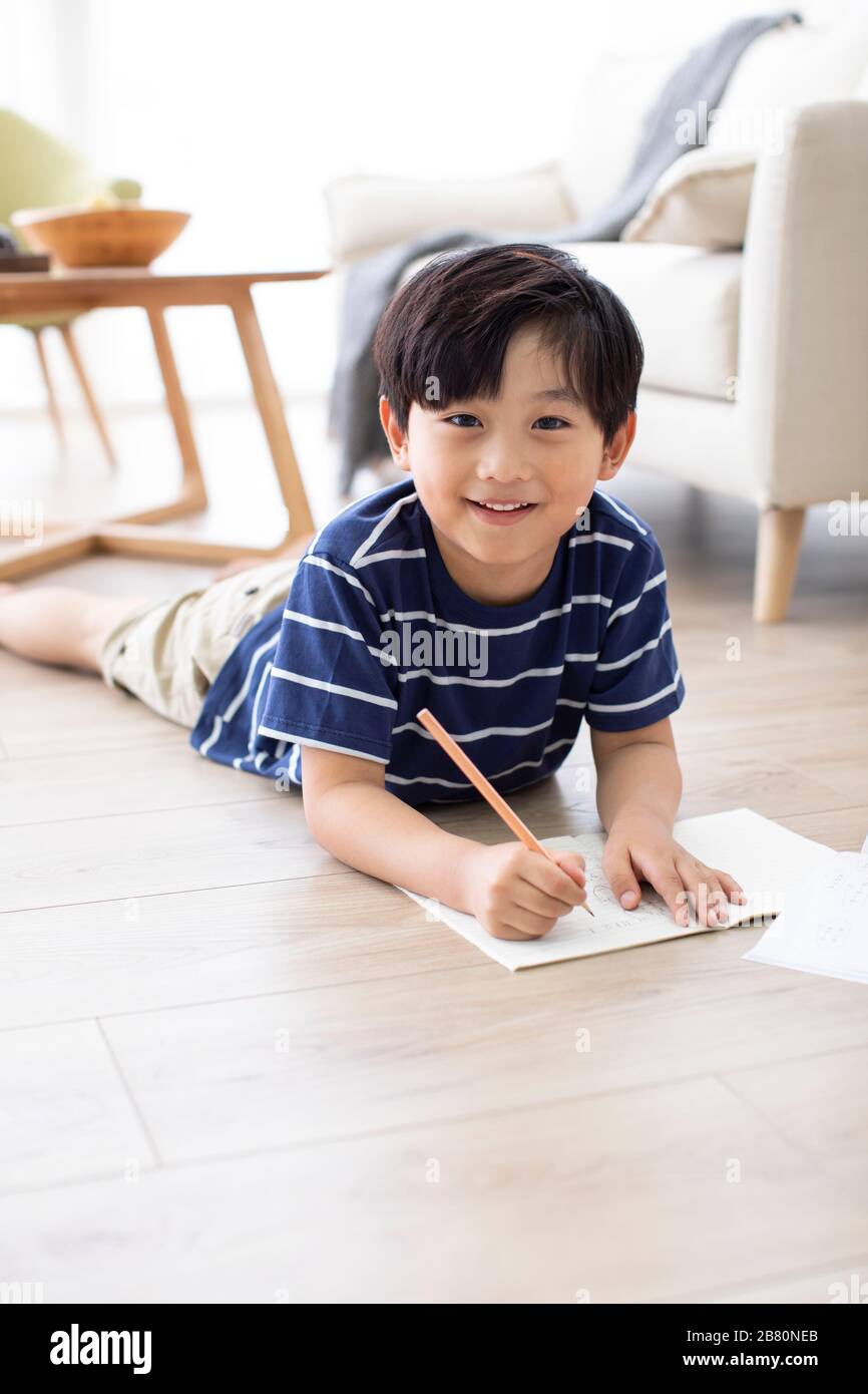 Little Chinese boy doing homework in living room Stock Photo - Alamy