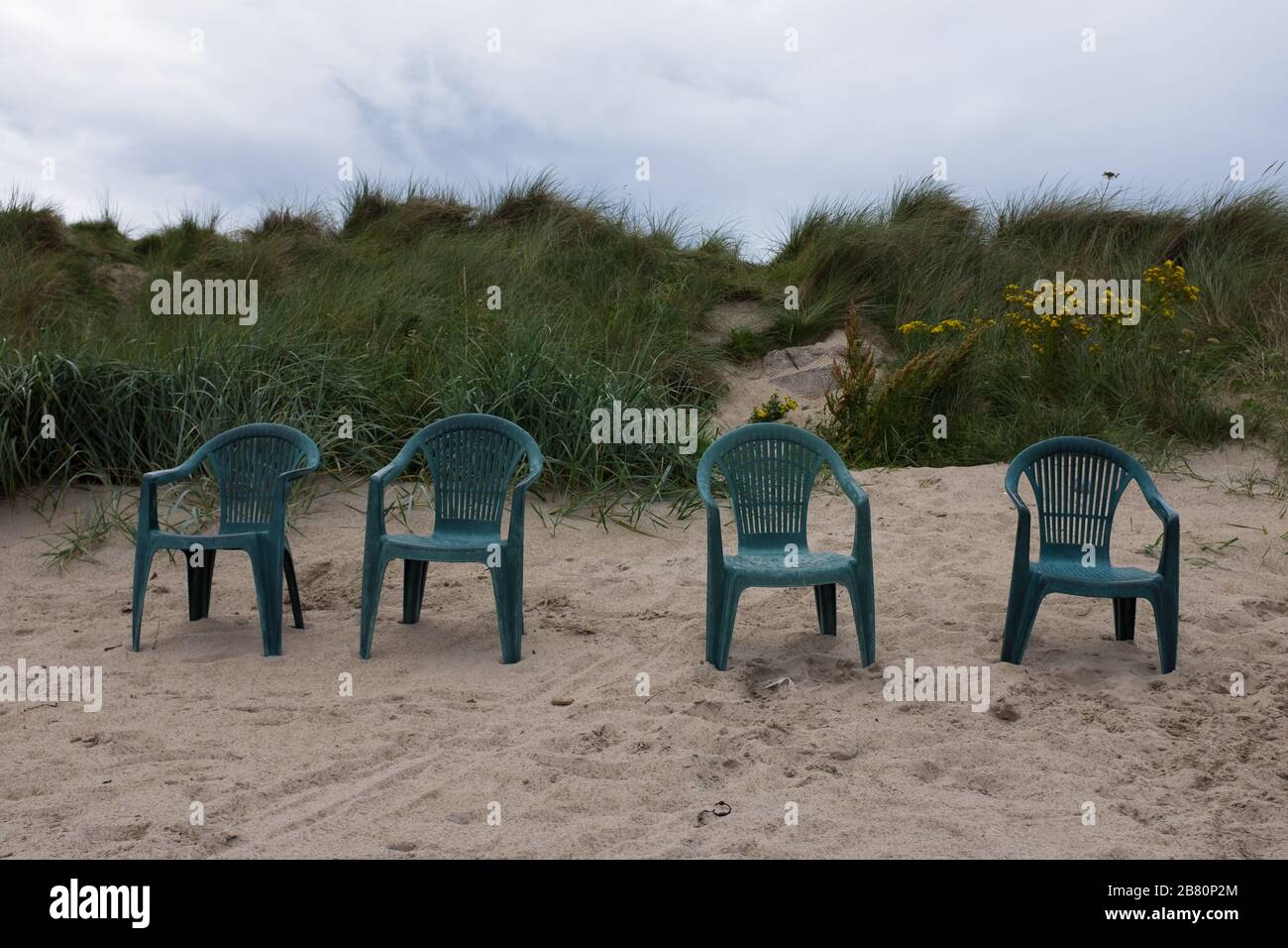 Four green lawn chairs on a beach Stock Photo - Alamy