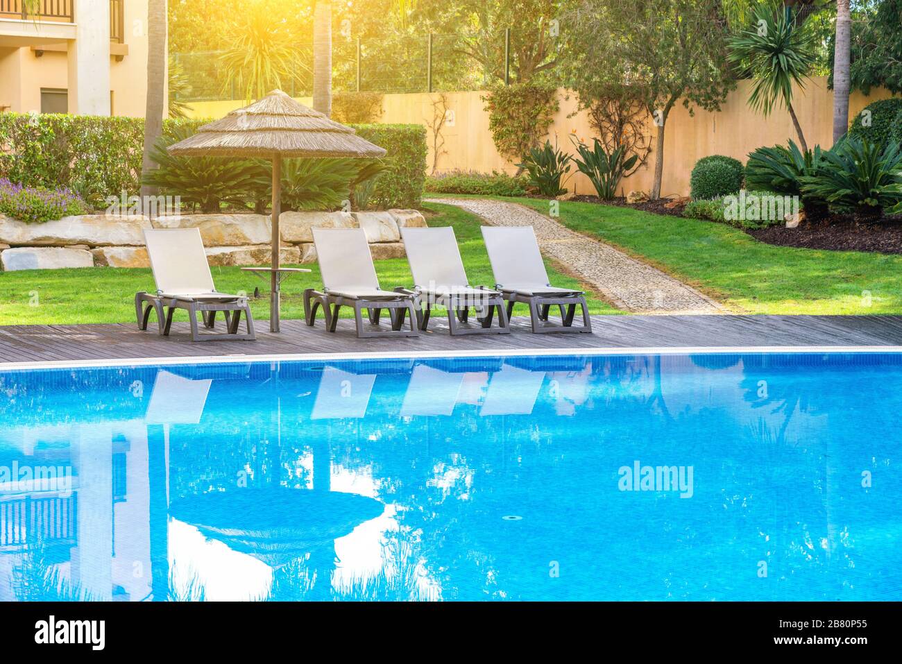 Pool with sun beds and umbrella for tourists at the hotel. Sunny day ...
