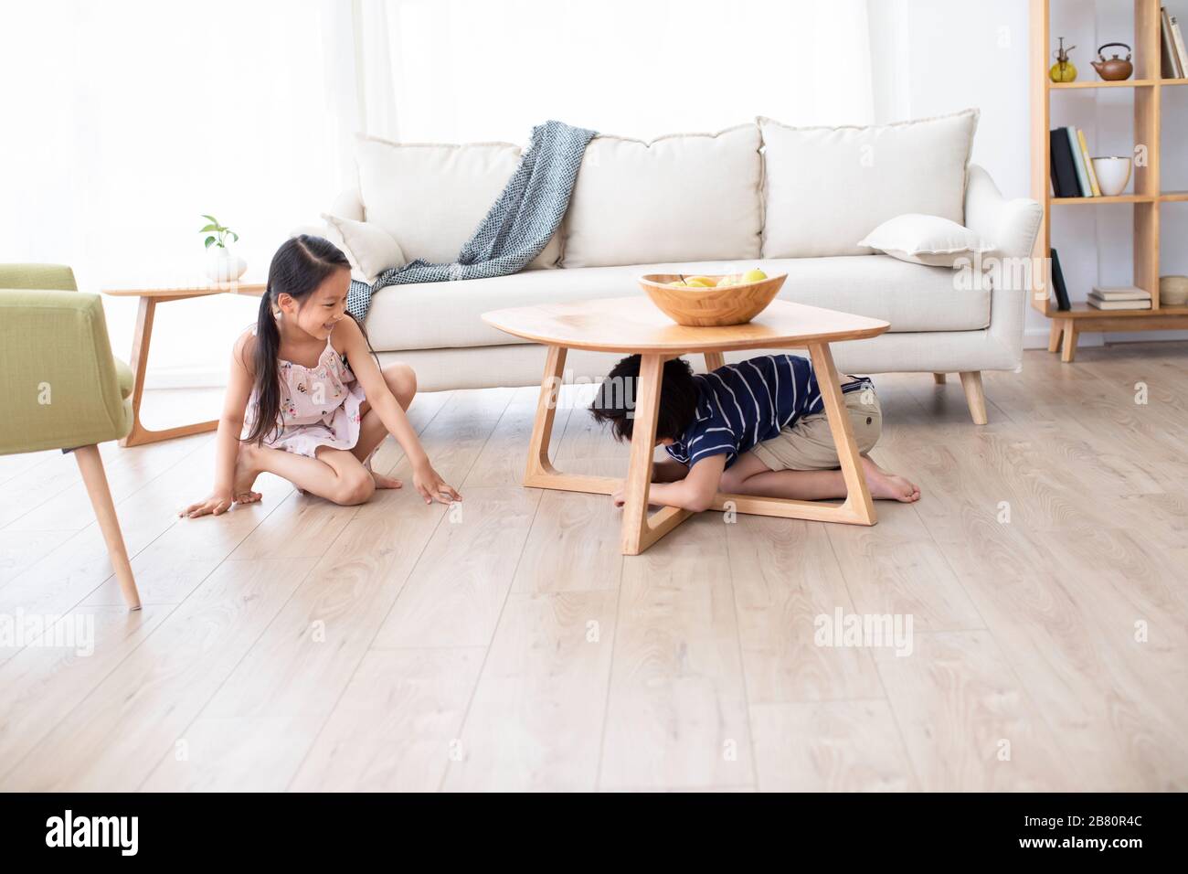 Happy Chinese sibling playing hide and seek in living room Stock Photo ...
