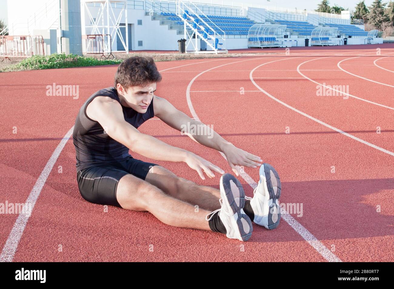 A young man makes an athlete stretching. Against the background the ...