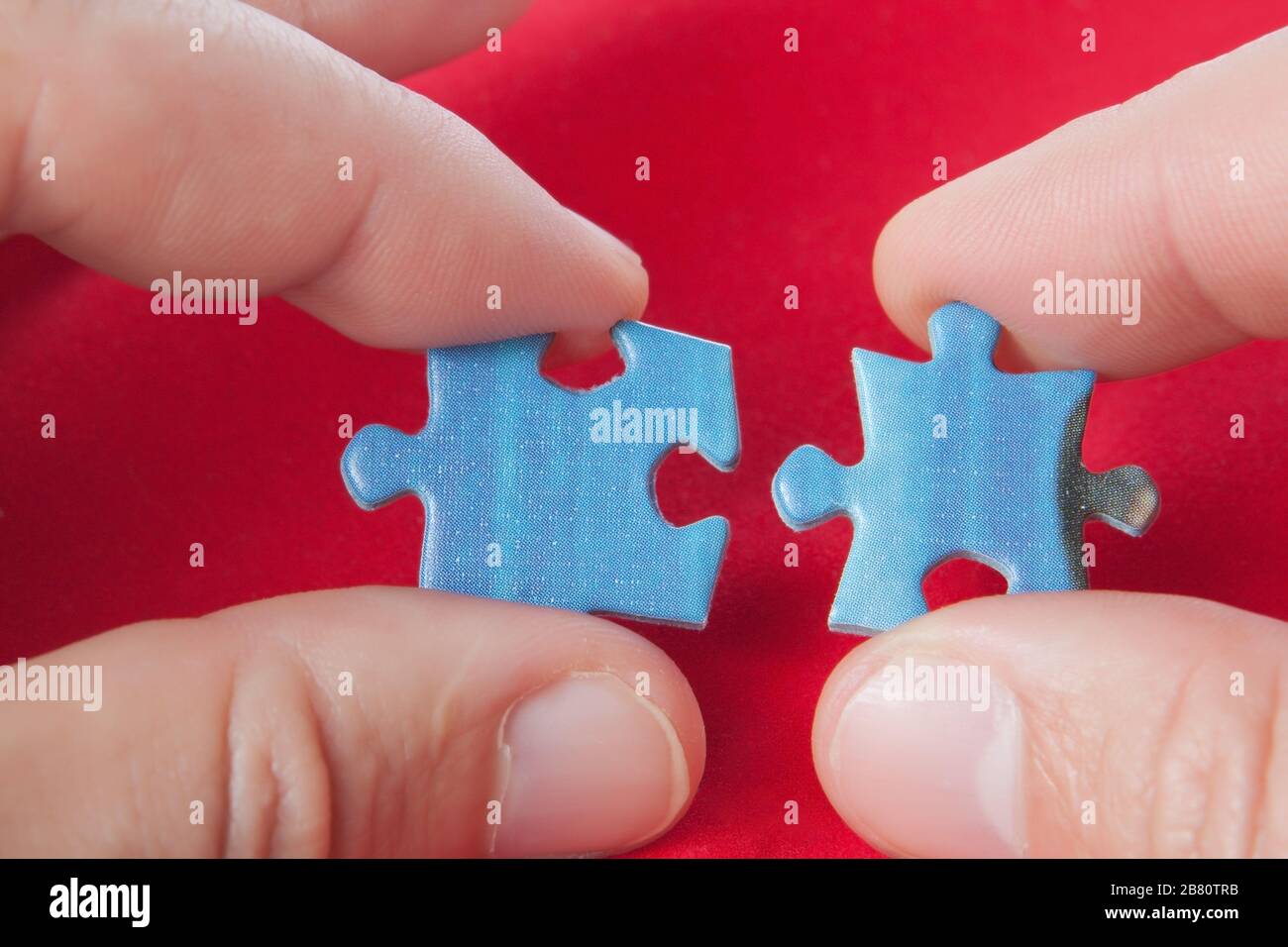 Connecting two puzzles. On a red background Stock Photo - Alamy