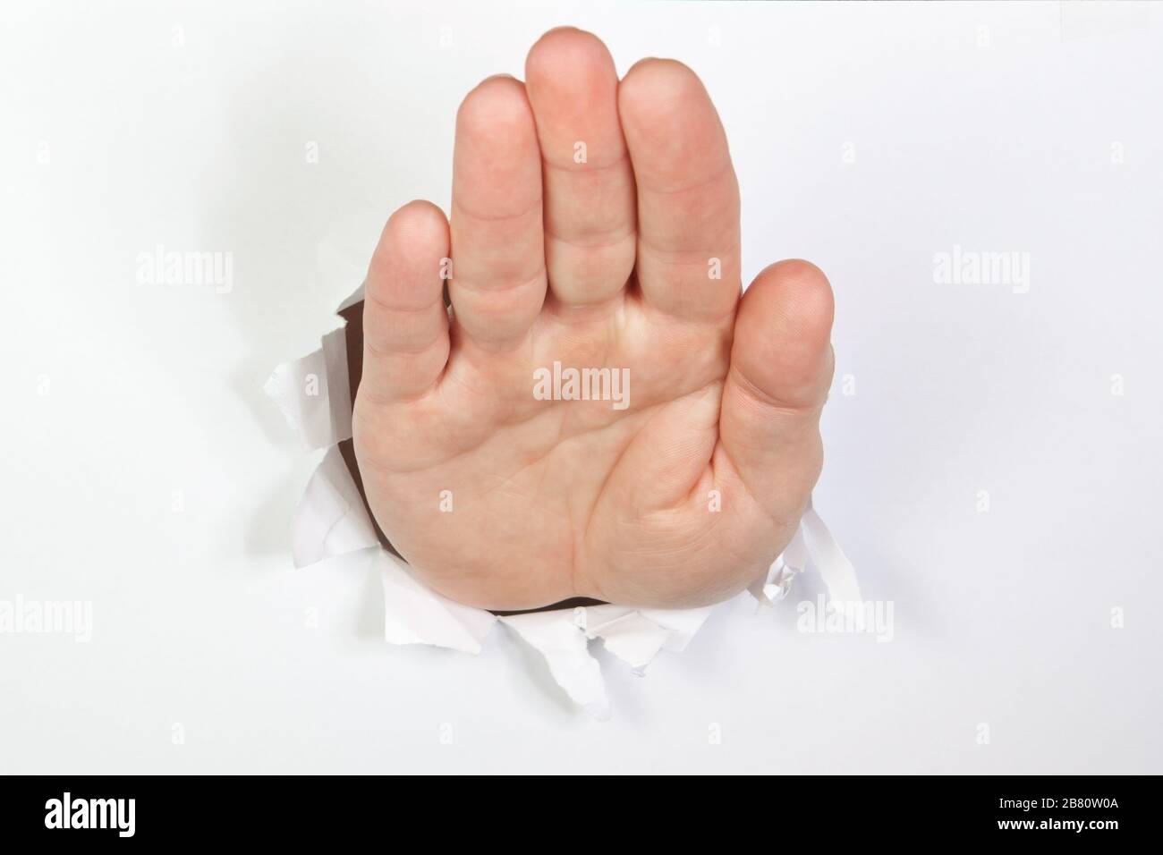 Greeting hand through a hole in the white paper Stock Photo - Alamy