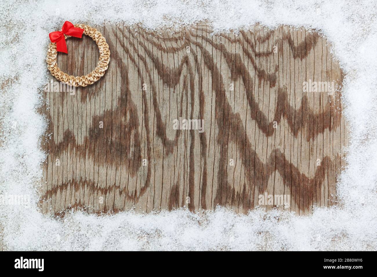 Snow frame and straw wreath with a bow on a wooden texture. For ...