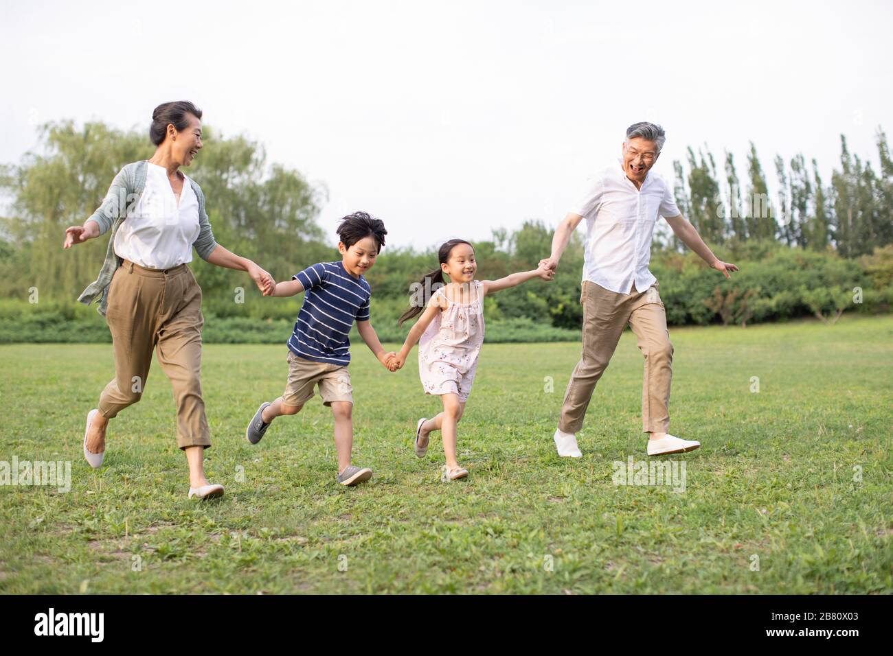 Happy Chinese family running on grass Stock Photo - Alamy